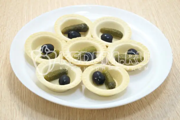 Set in gherkin en in pitted olive yn elke tartlet.