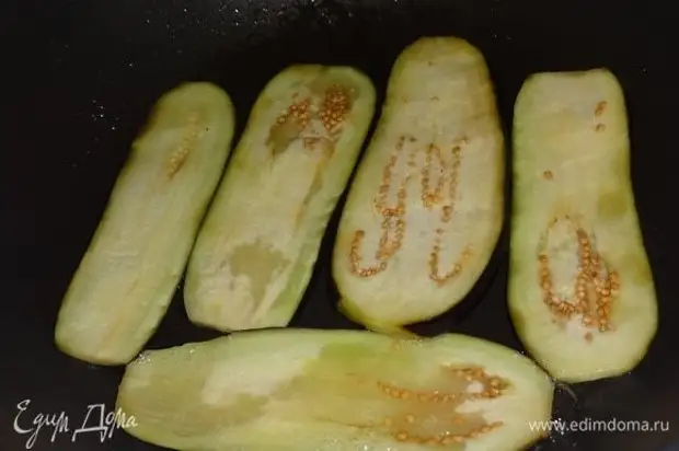 Når tiden er gået, fjernes auberginepladerne fra vandet og tørres. Hæld vegetabilsk olie i en stegepande, opvarm. Læg auberginepladerne og steg først på den ene side, indtil de er gyldenbrune.